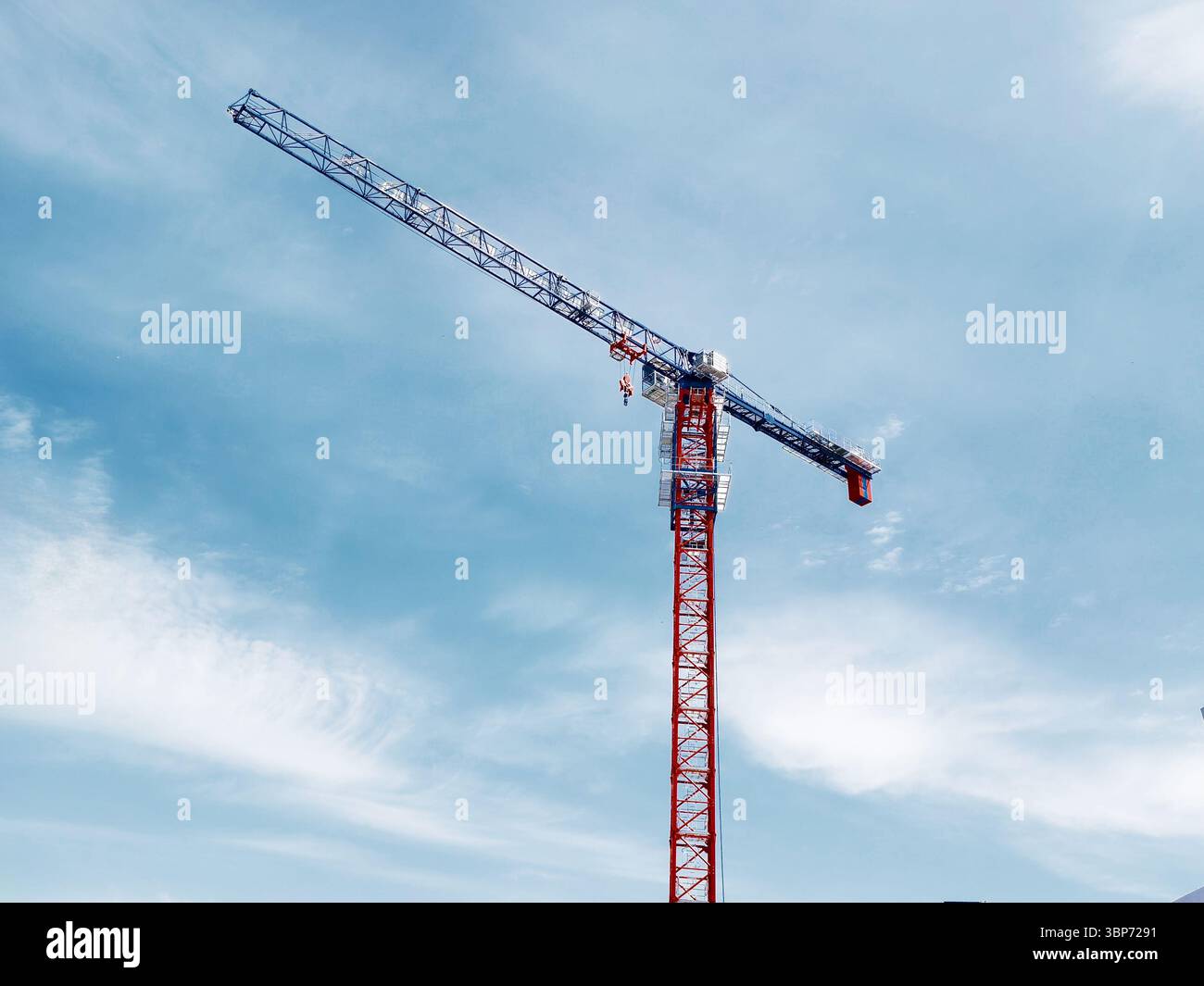 Construction crane stands tall against a clear blue sky near a building site in an urban area ...
