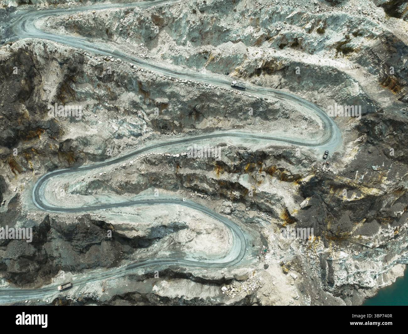 Drone shot capturing heavy machinery moving through terraced quarry ...