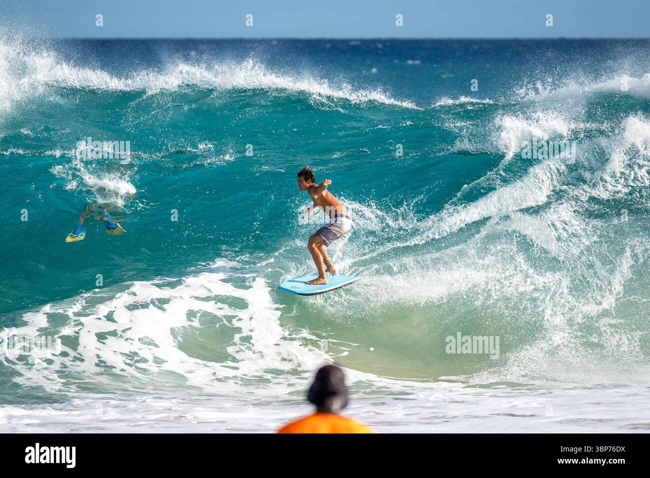 Surfer carves through a towering turquoise wave, muscles tense and ...