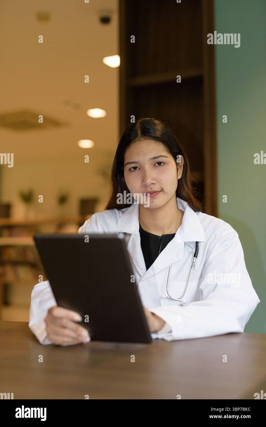 Young Asian woman doctor wearing white lab coat and stethoscope sitting ...