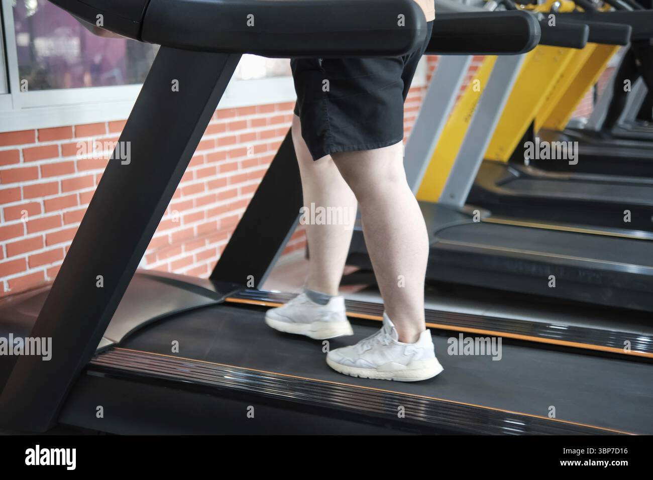 A person is running on a treadmill in a gym. The person is wearing ...