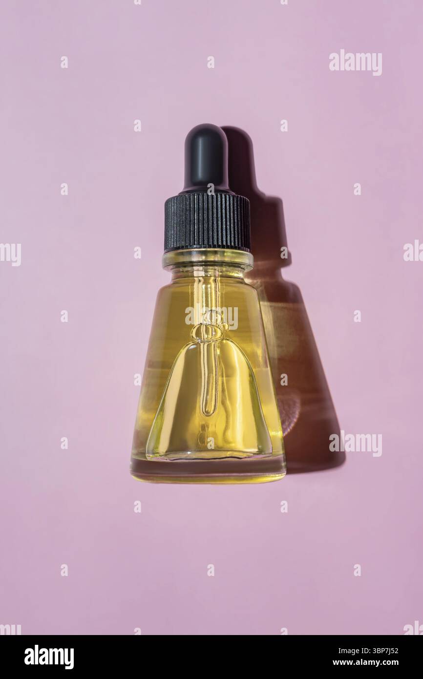 Anti aging serum in glass bottle with dropper on pink background ...