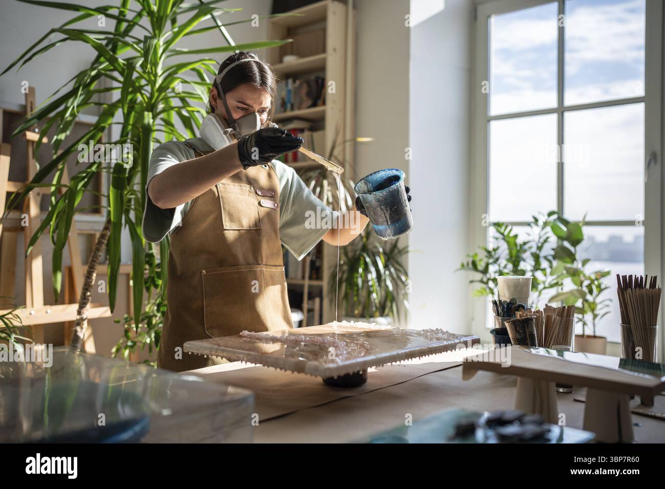 Serious female artist works with epoxy resin, creating picture in ...