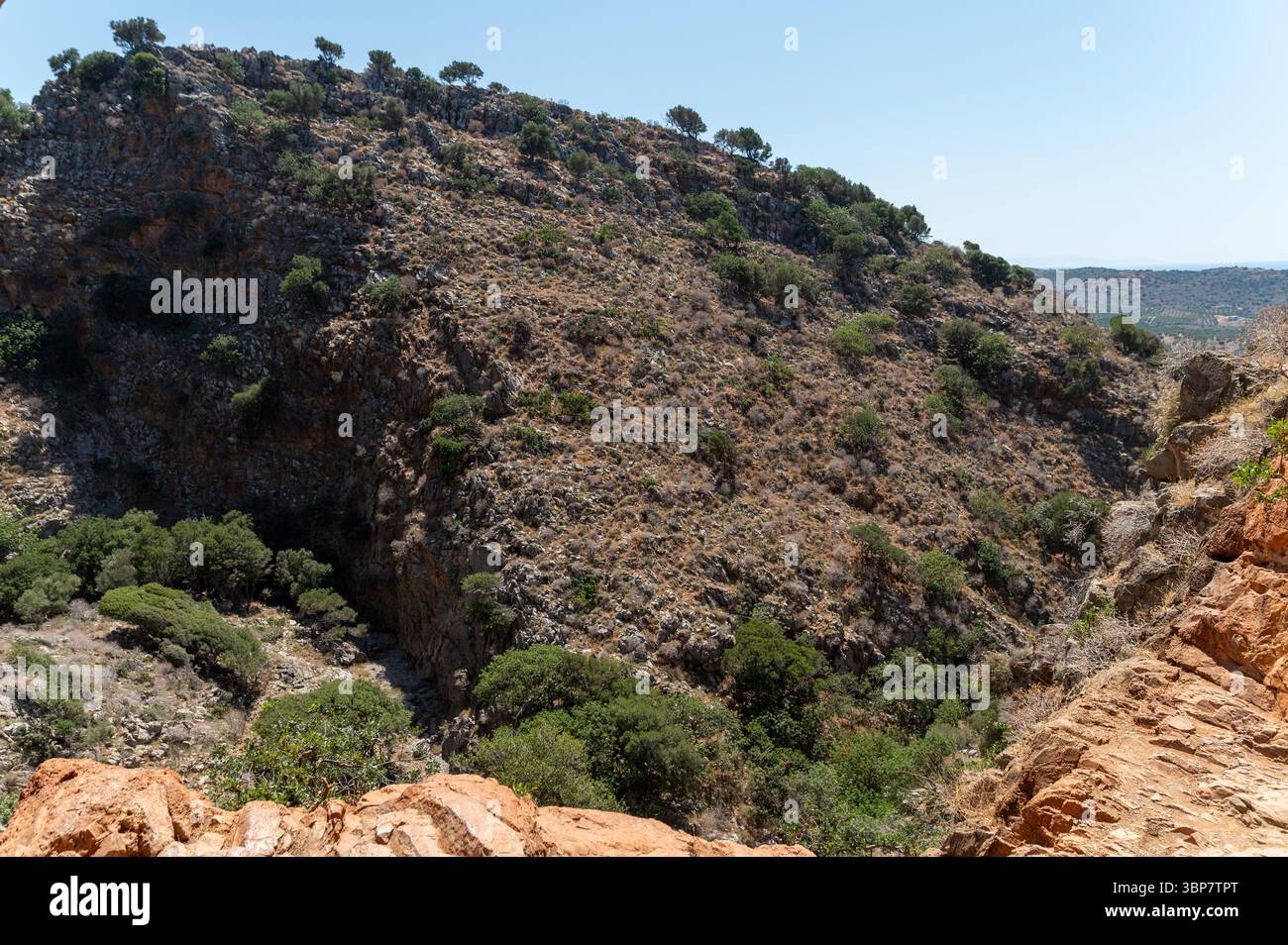 Visitors admire the rugged terrain surrounding Milatos Cave, Crete ...