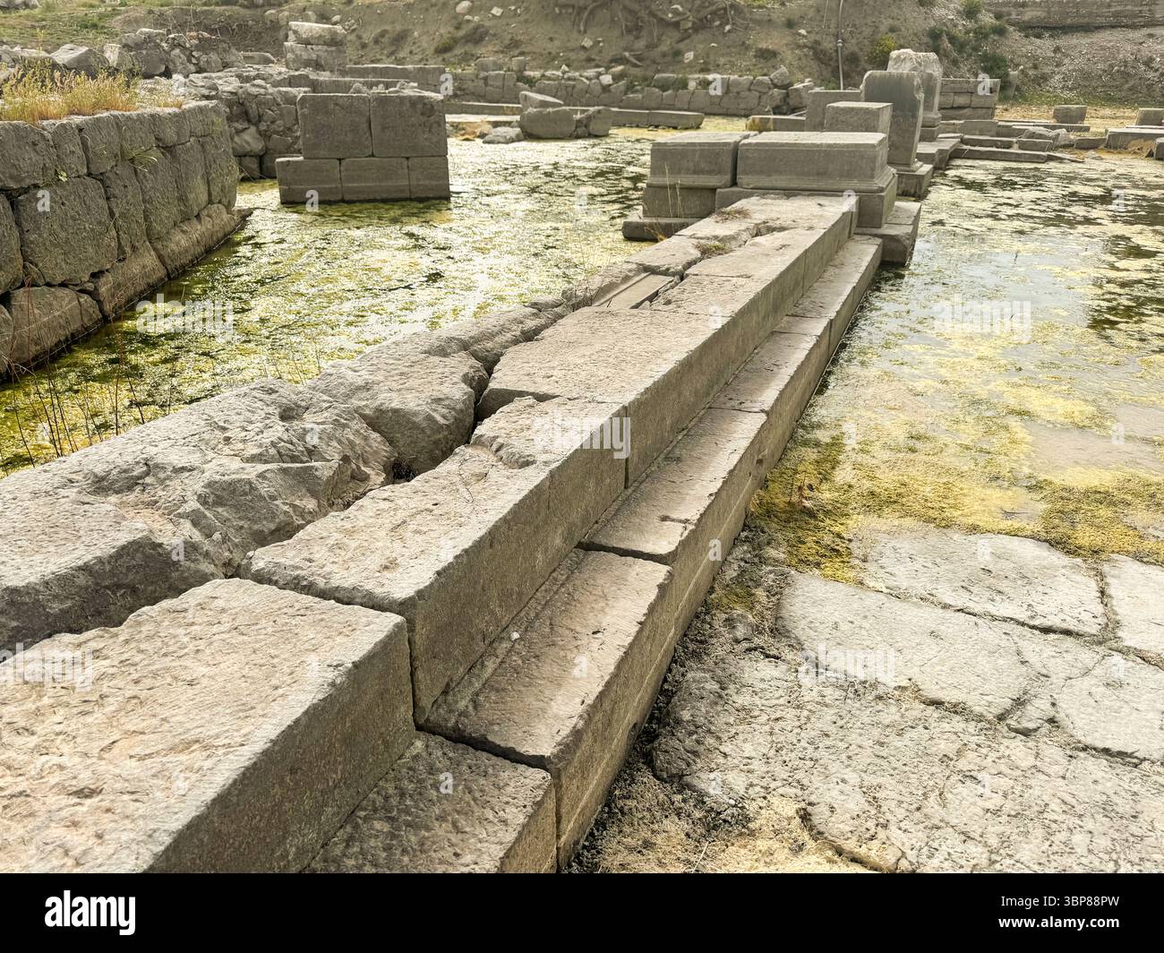 Ancient stone structures near water with moss and vegetation in a ...