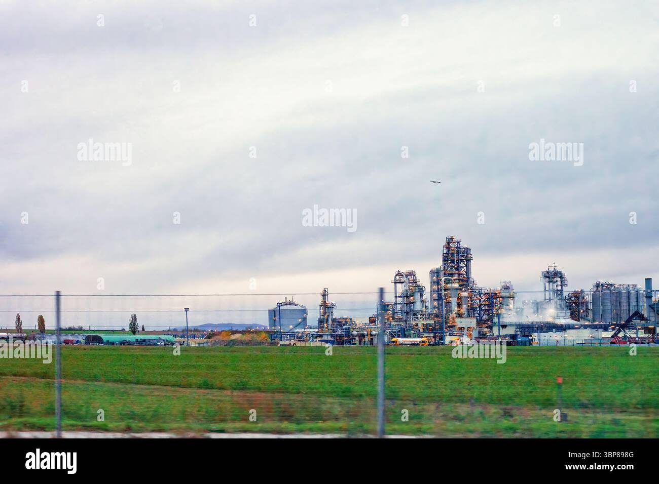 Crude oil refinery plant and green meadow. Summer scenic with fields ...