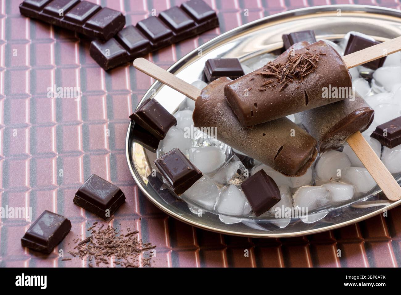 Melted chocolate ice cream sits on a silver plate surrounded by ice and ...