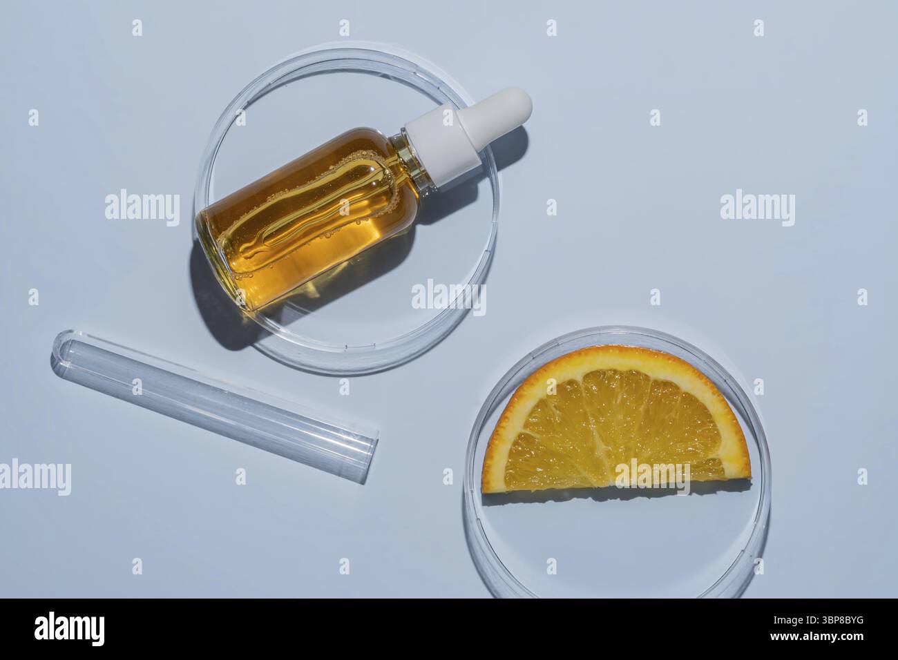 Dropper bottle with orange serum with vitamin C in a petri dish next to ...