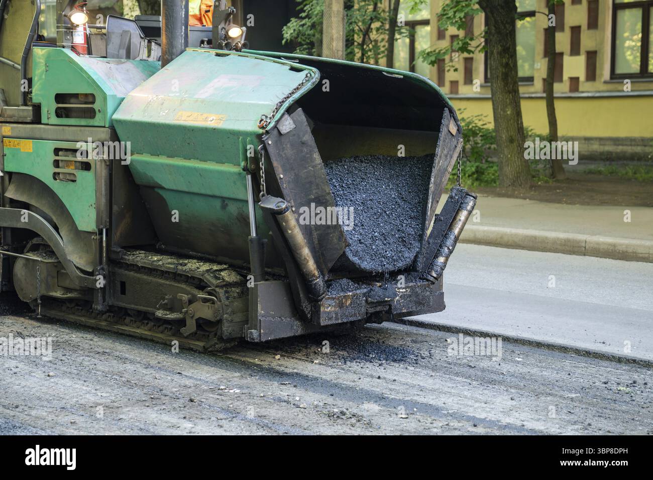 Construction vehicle is pouring asphalt to create smooth road surface ...