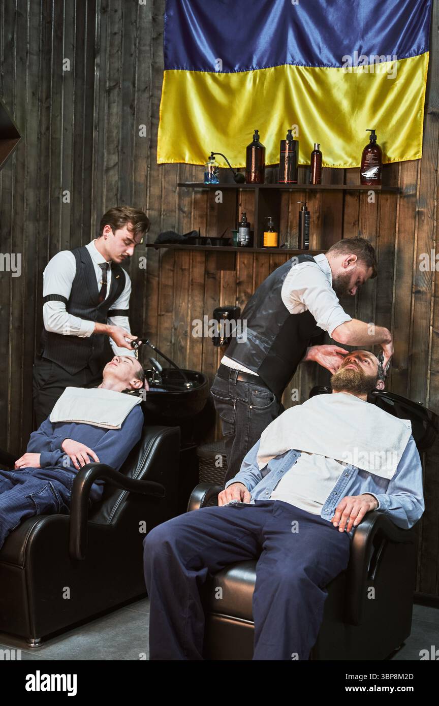 Professional barbers washing hair with deep cleaning shampoo. Busy day ...