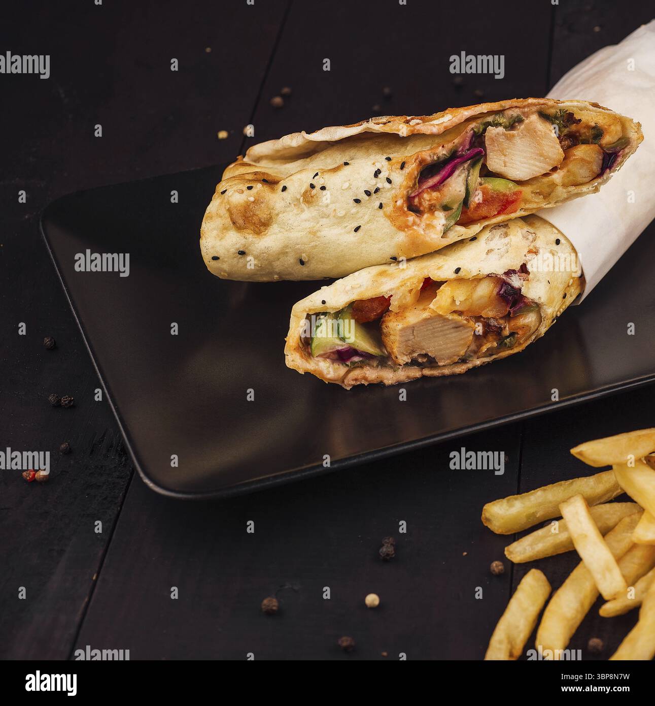 Food, Chicken shawarma wrap cut in half lying on a black plate with ...