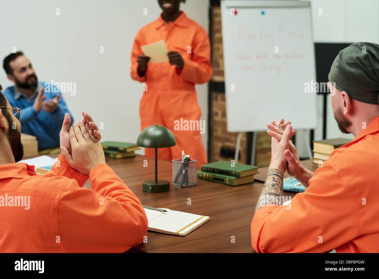Diverse group of adult men in orange uniforms attending educational ...