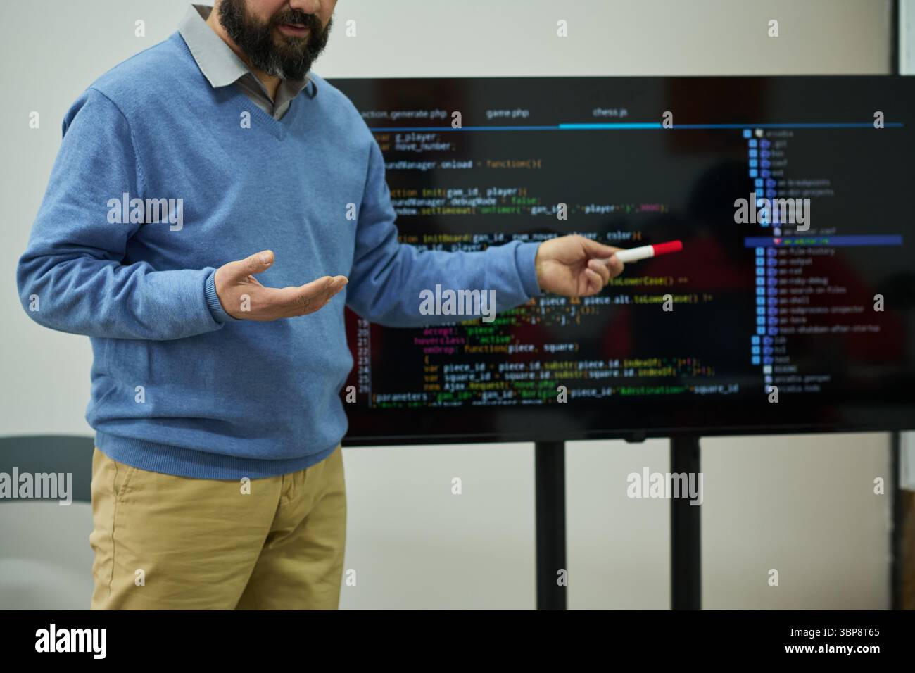 Middle aged Caucasian man teaching programming in prison classroom, holding marker and gesturing ...
