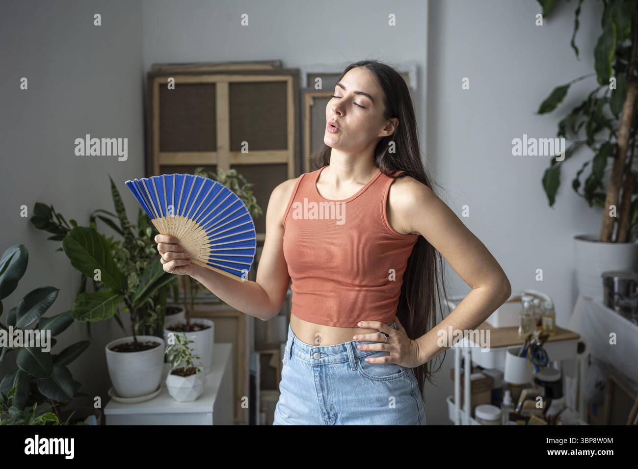 Exhausted woman suffers from heat fanning with paper fan. Stressed ...
