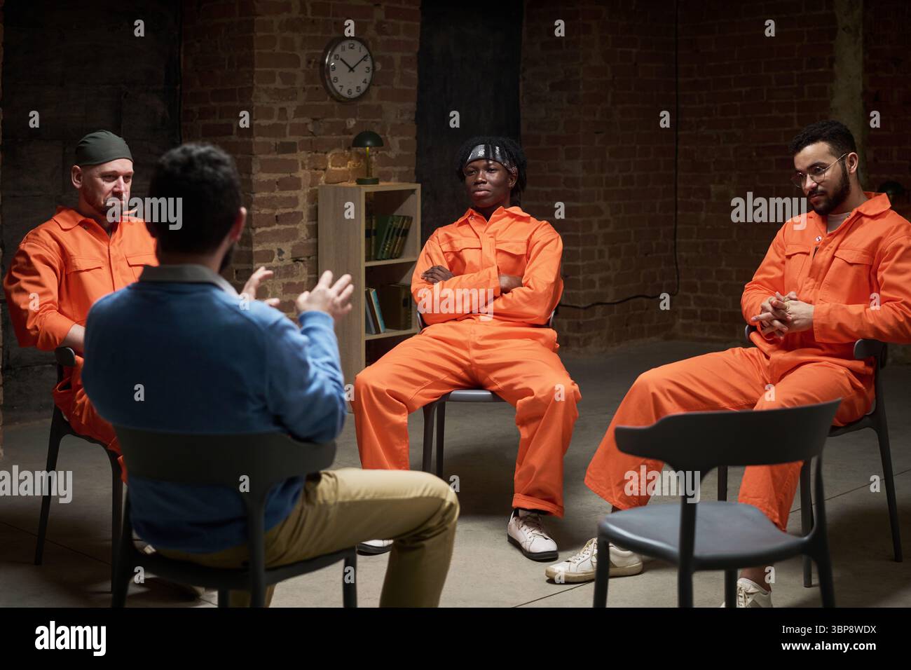 Group of young adult male inmates in orange jumpsuits sitting in circle ...