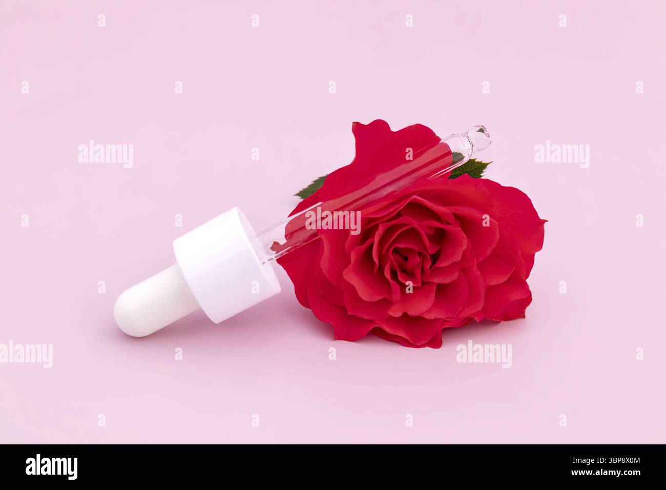 Cosmetic serum pipette with face beauty serum inside on a pink ...