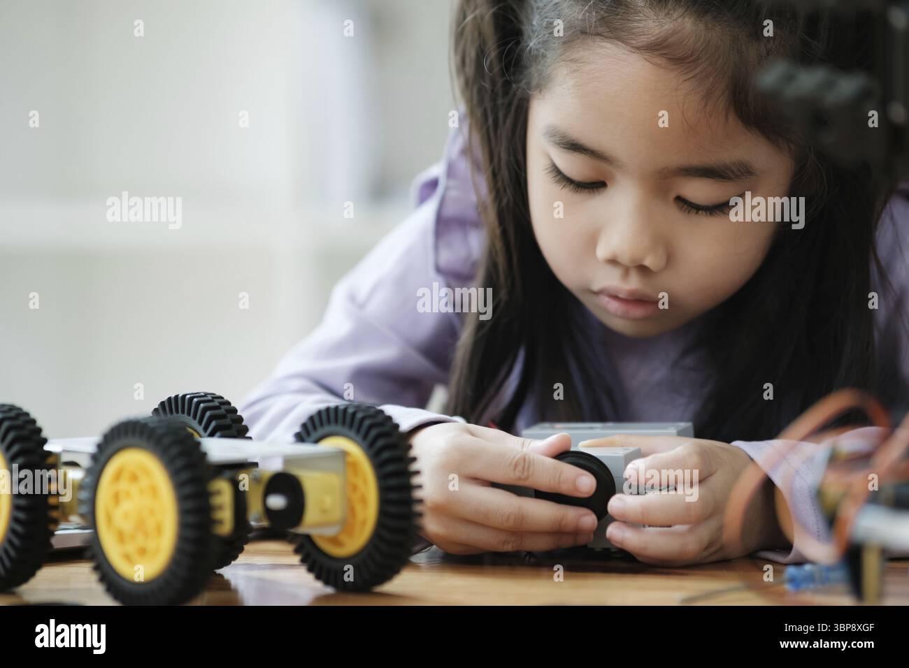 Asian girl concentrating on building a robot, embodying STEM education ...