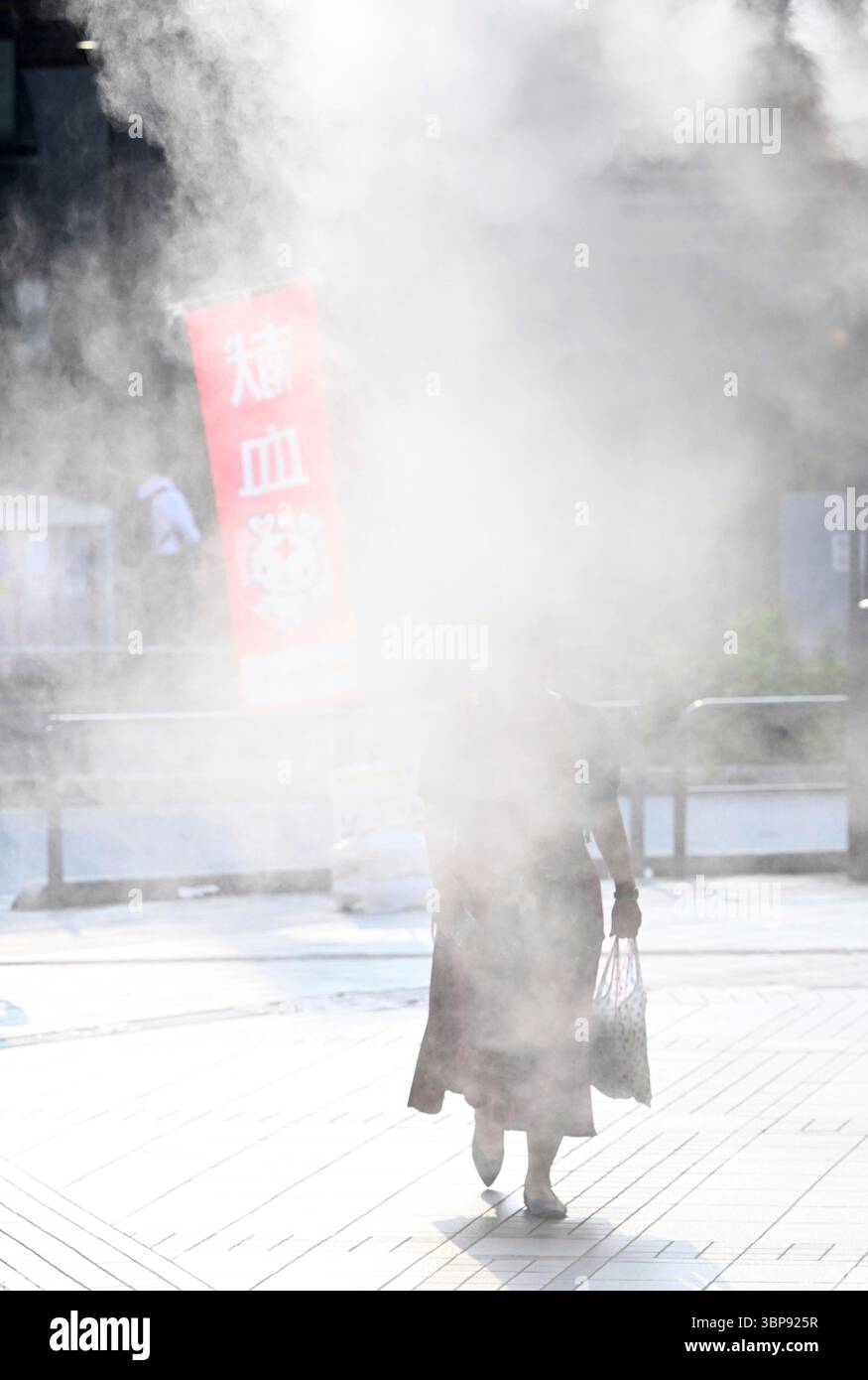 People walk under the mist spewing out while the temperature rising in ...