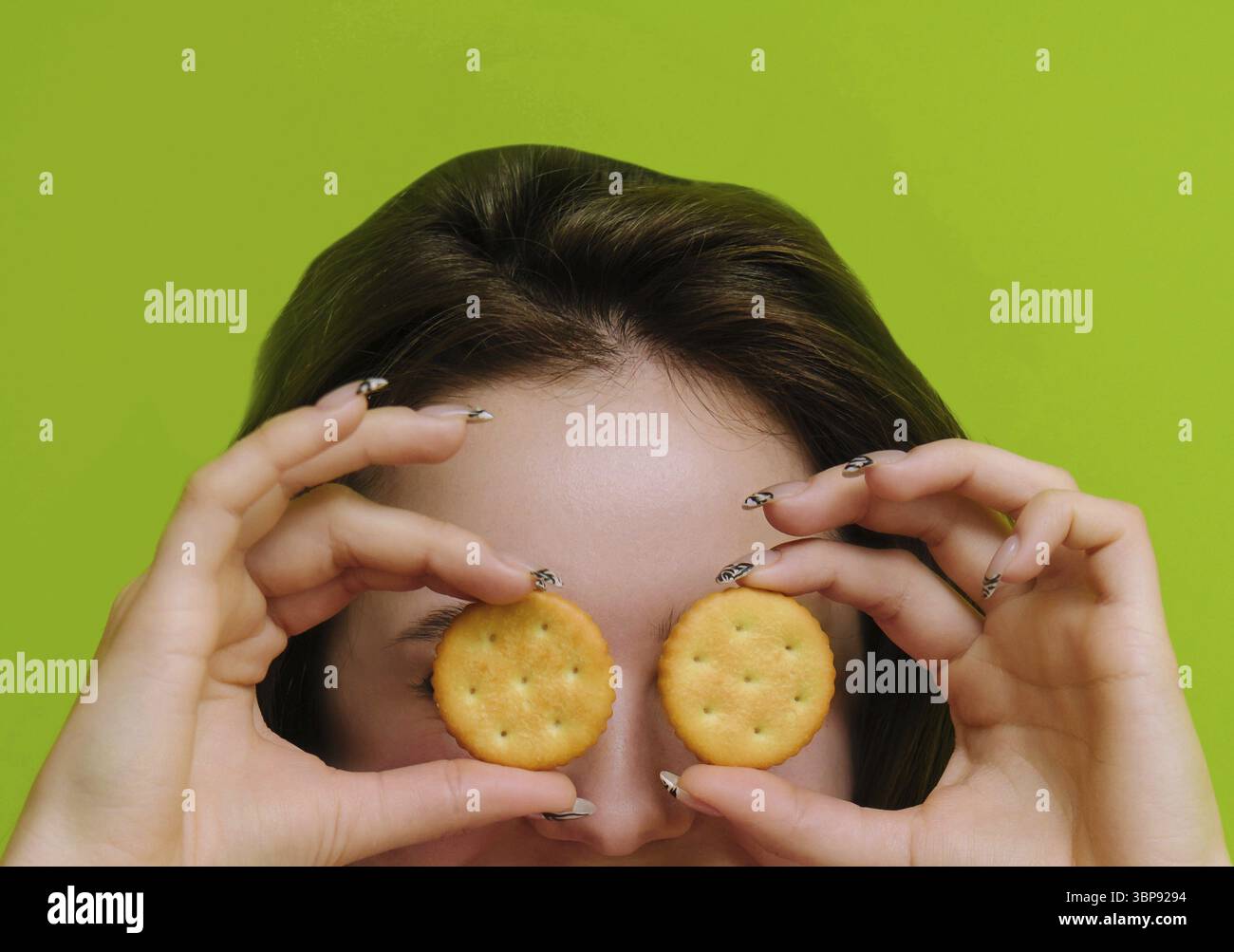 Food, Young woman is playfully holding round crackers over her eyes and ...