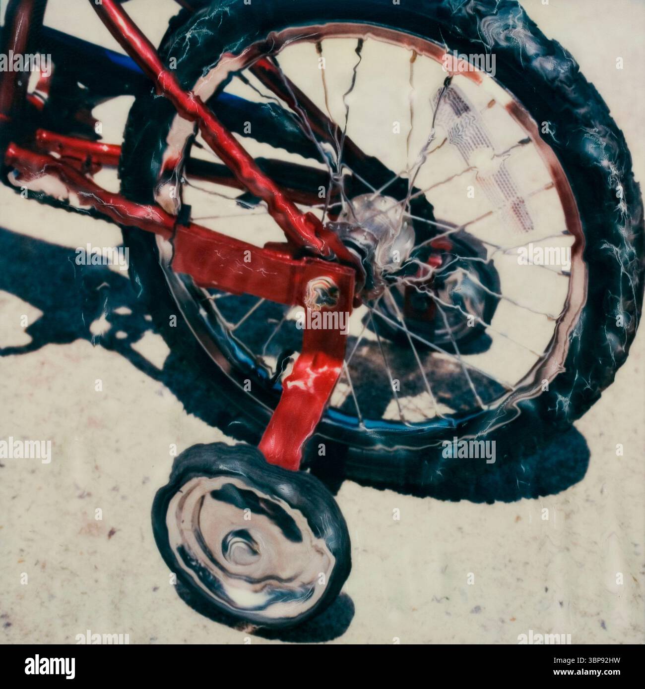 Polaroid manipulation a child's red bicycle with training wheels Stock ...