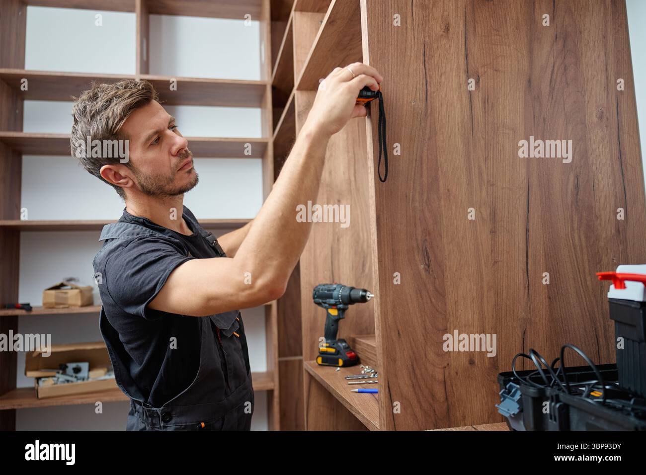 Close-up of man measuring wooden wardrobe with tape measure during ...