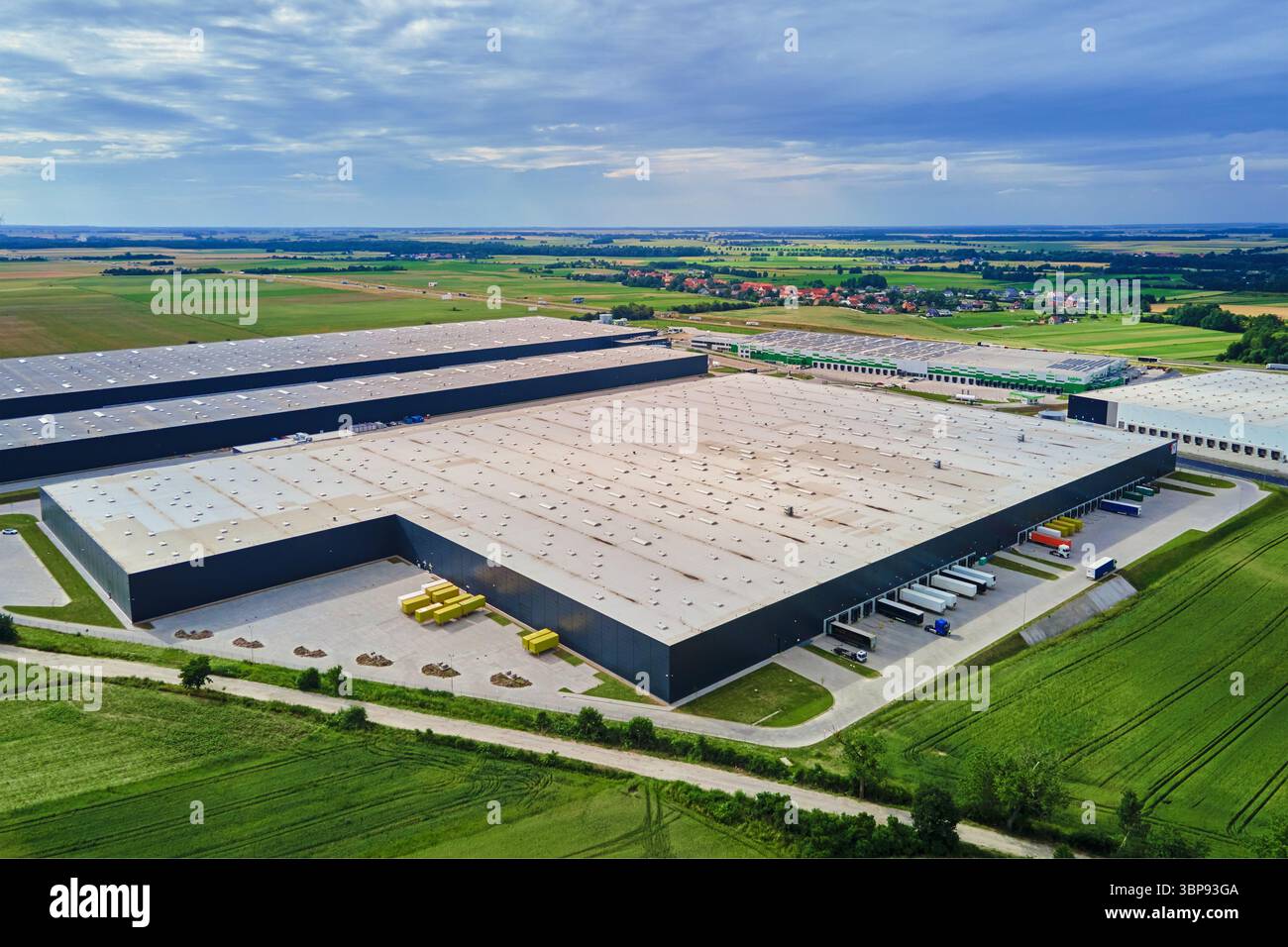 Large modern warehouse with loading docks and parked trucks surrounded ...