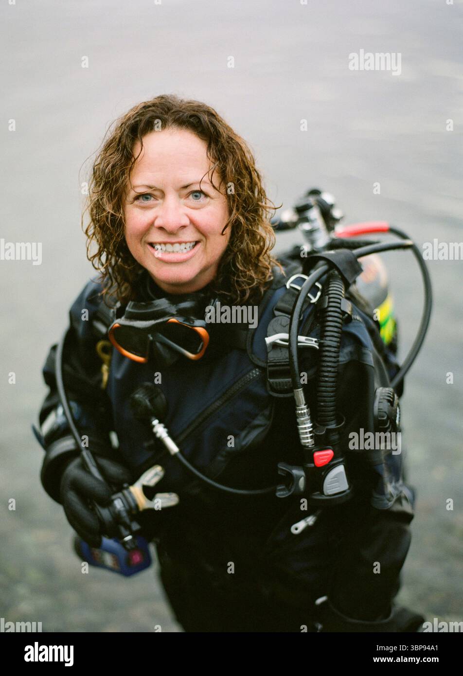 A female scuba diver smiles at the waters edge at the beach Stock Photo ...