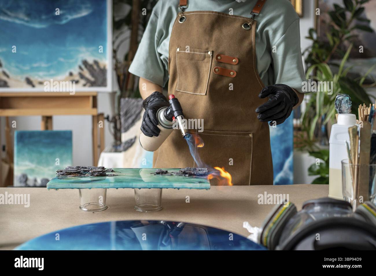 Hands of female artist burn epoxy resin painting with blowtorch hi-res ...