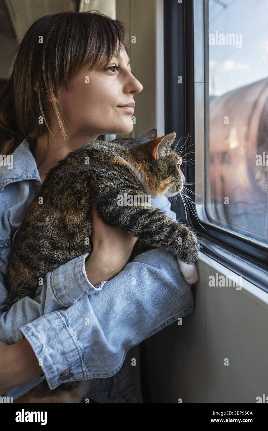 Satisfied girl holds calm cat in arms hugging embracing. Glad owner ...