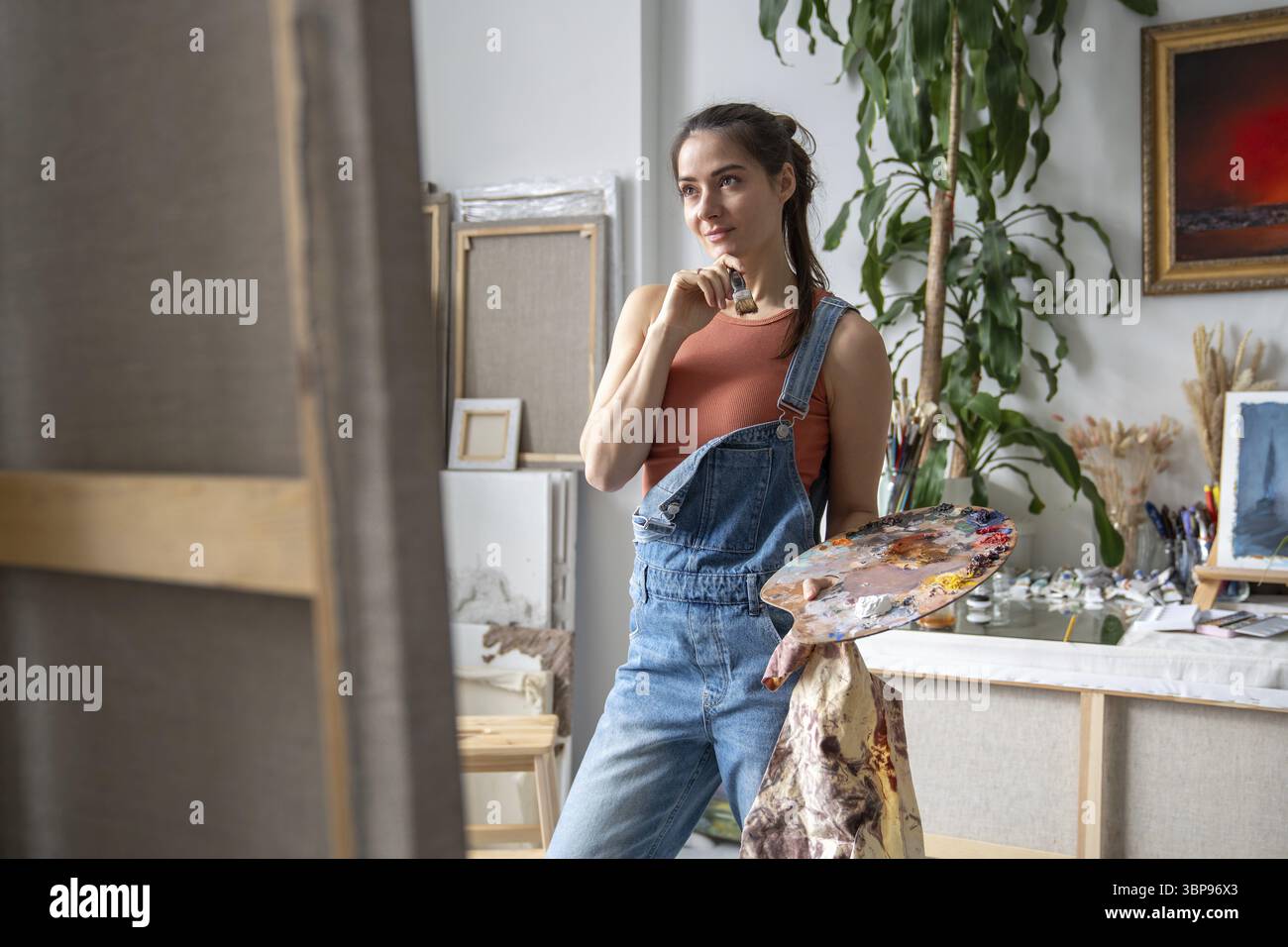 Inspired female artist reflects looking at painting. Smiling exited ...