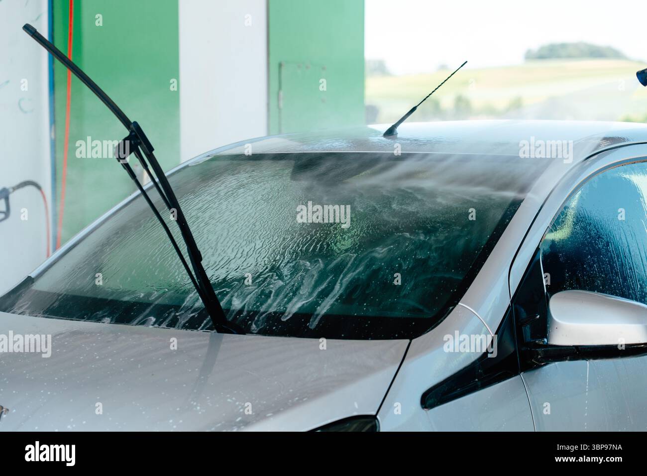 Car windshield covered in water during a thorough cleaning process at a ...