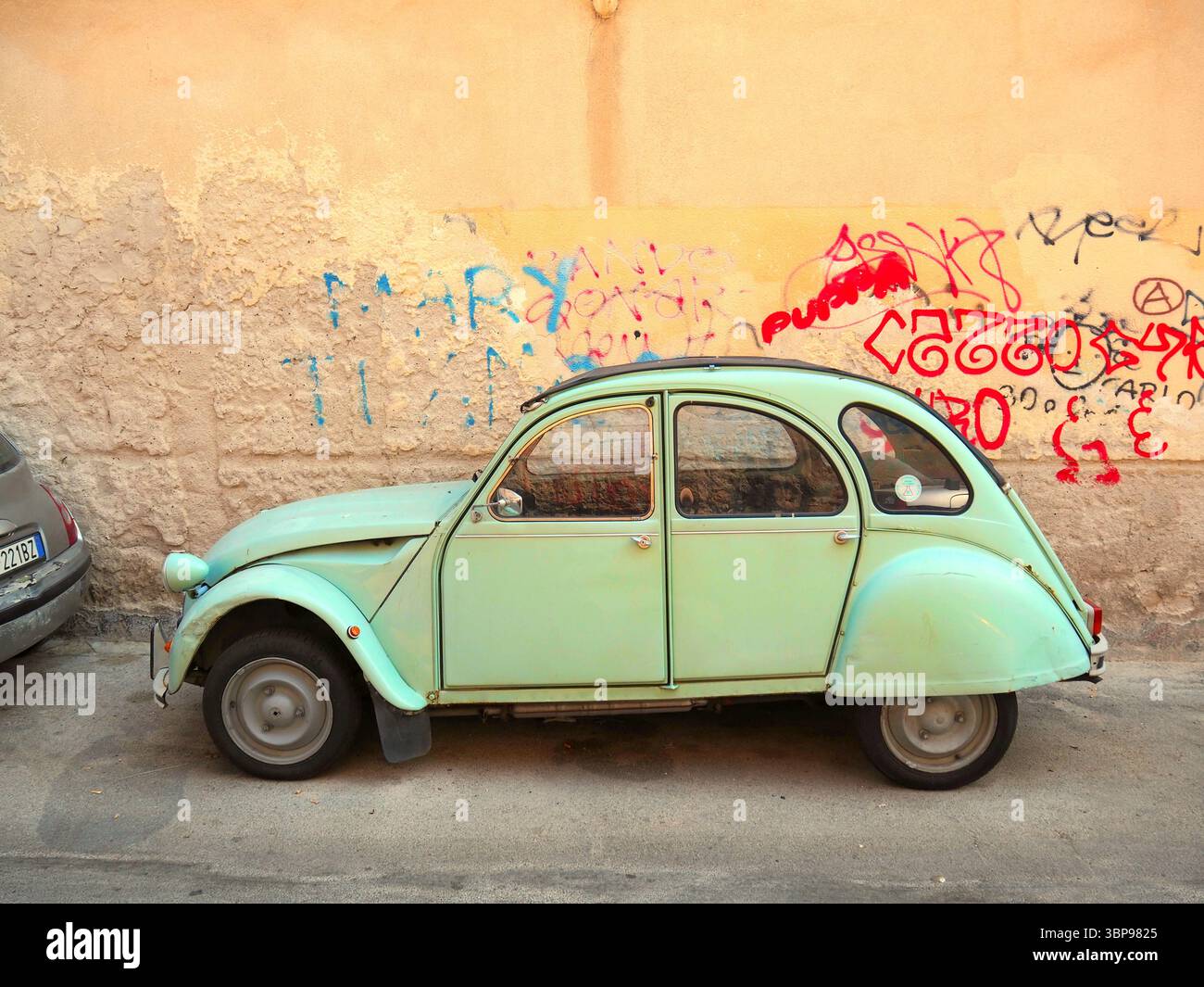 Vintage mint green Citroën car parked on colorful graffiti street in ...