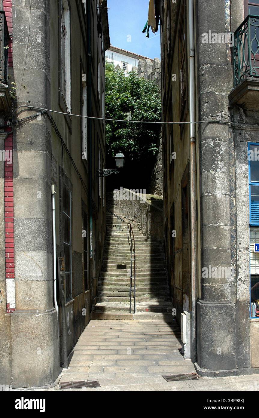 A narrow alleyway with a staircase leading upwards, flanked by aged ...