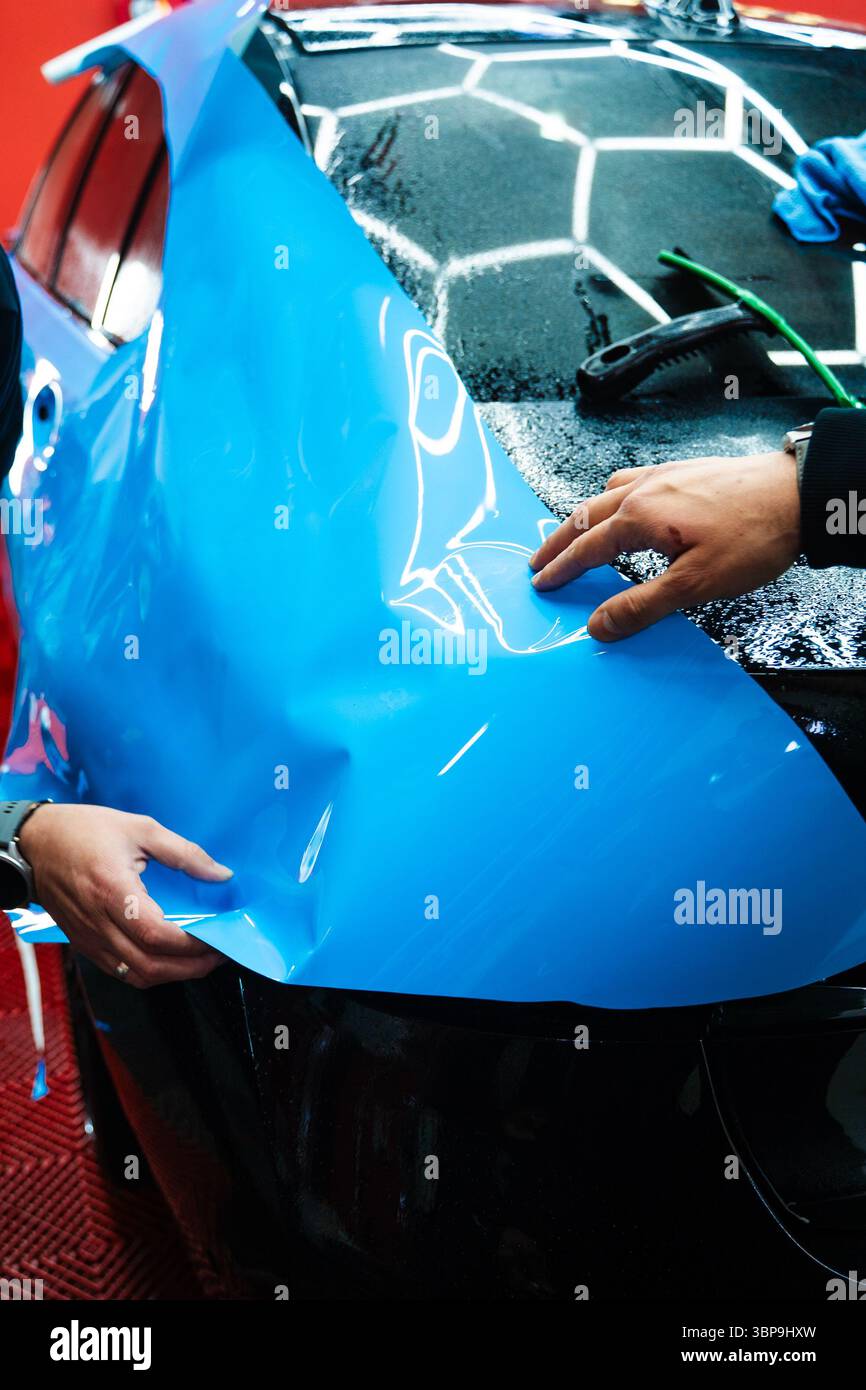 Applying PPF wrap on car during full detailing. Bold blue vinyl wrap ...