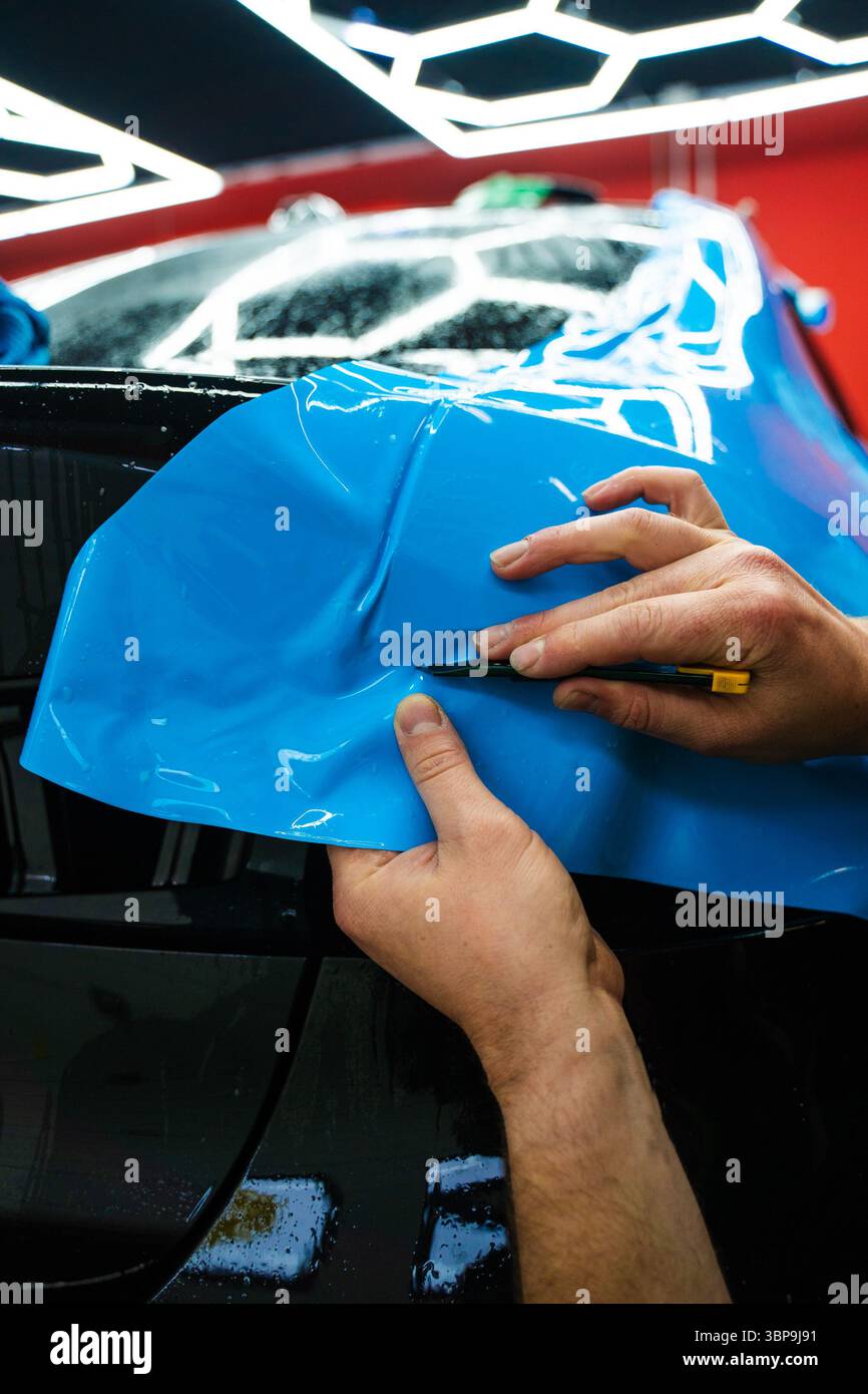 Cutting blue PPF with blade. Cutting blue paint protection film with ...