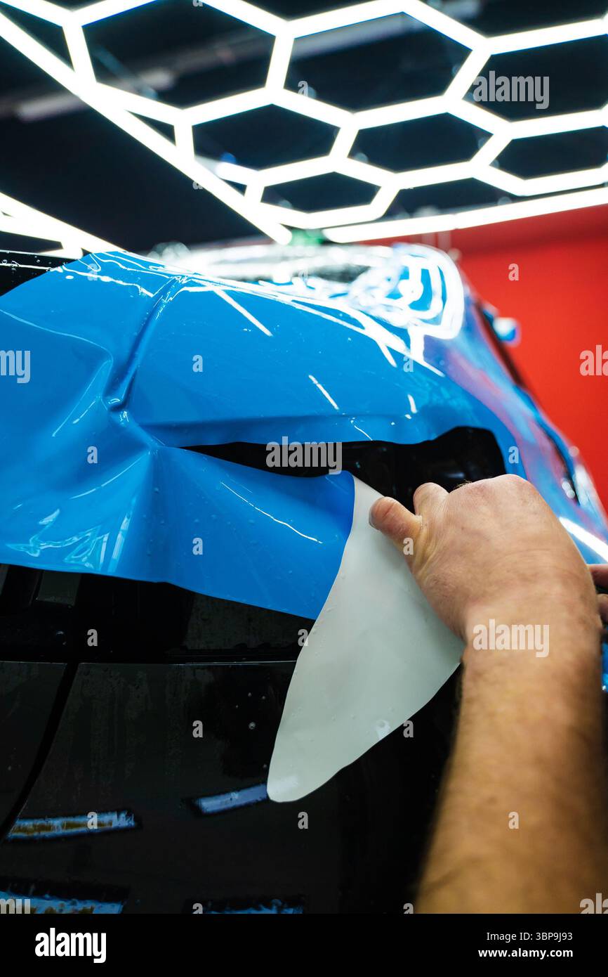 Cutting blue PPF with blade. Cutting blue paint protection film with ...