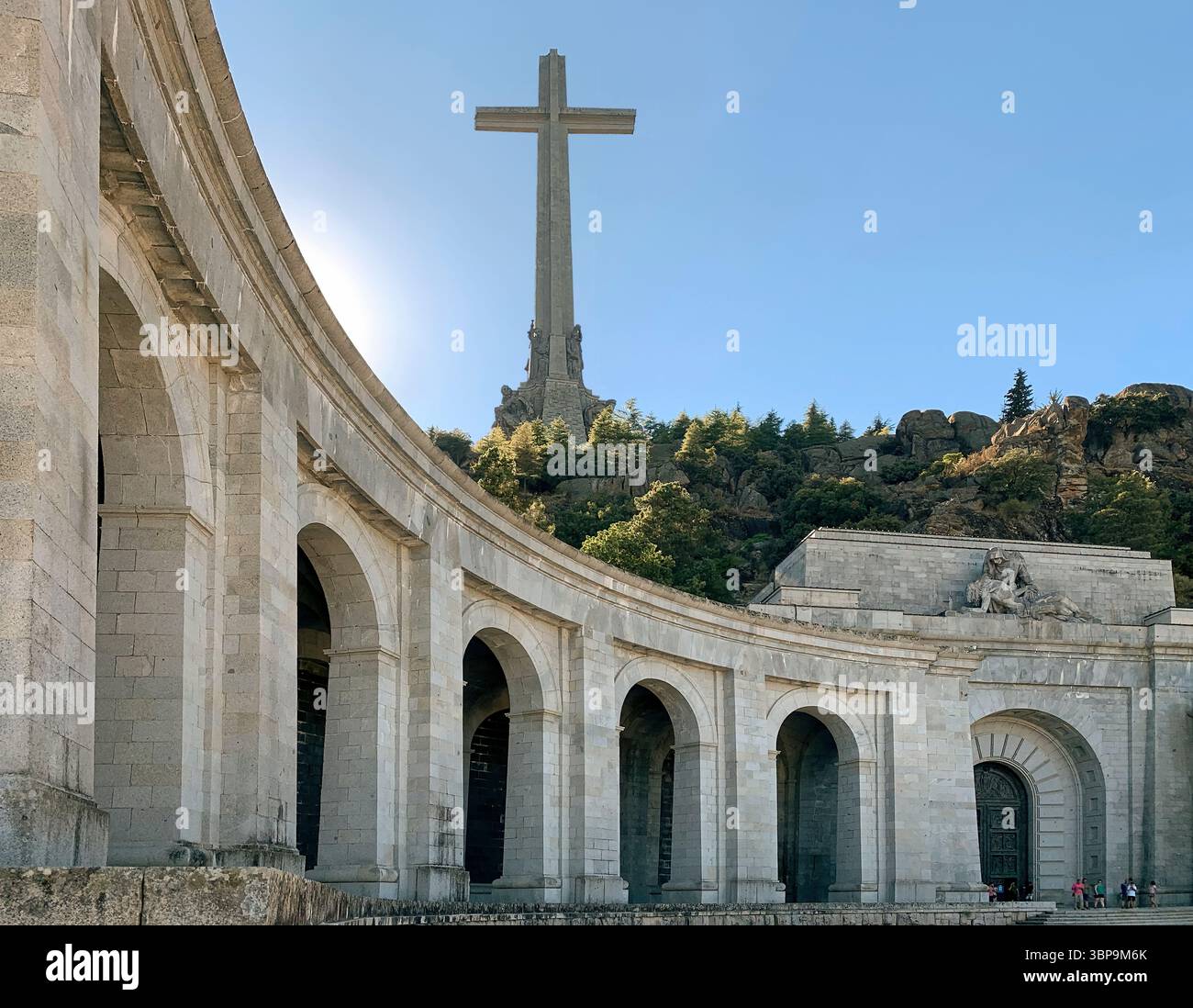Stone archways and cross monument with hills and trees under a clear ...