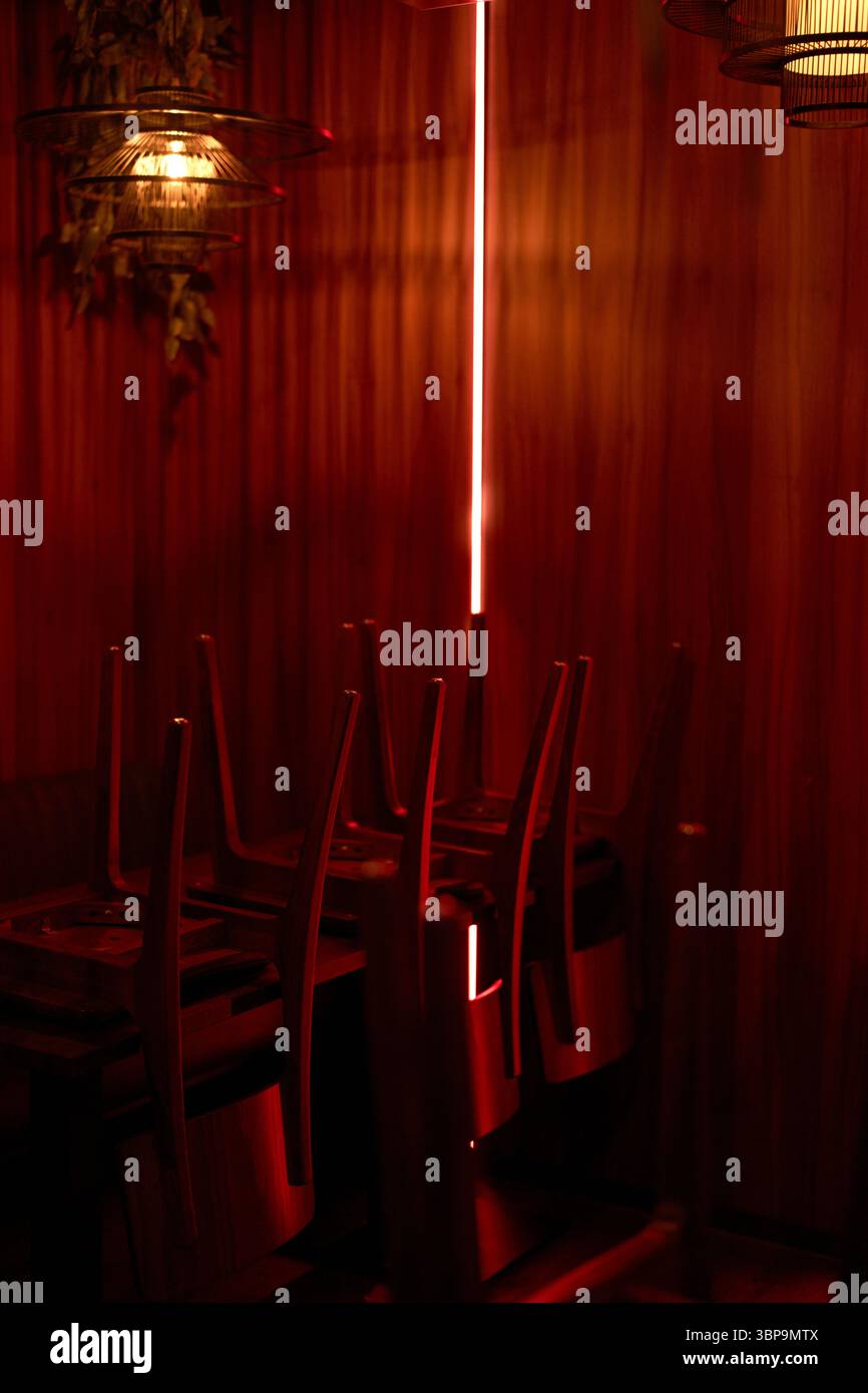 Dimly lit restaurant with wooden walls and chairs stacked on tables ...