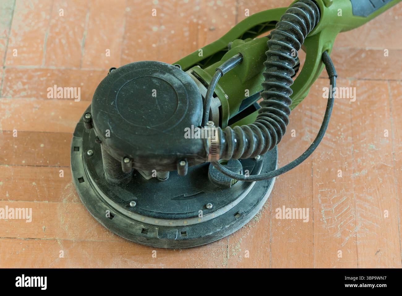 A close-up view shows an olive green electric random orbital sander ...