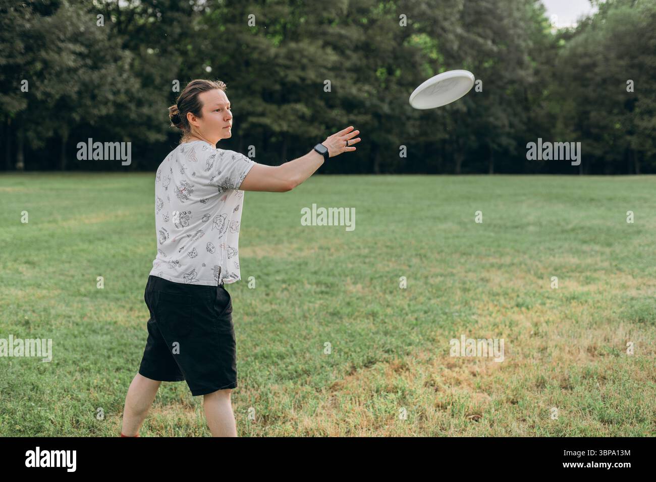 Man releasing flying frisbee with extended arm over open green grass ...