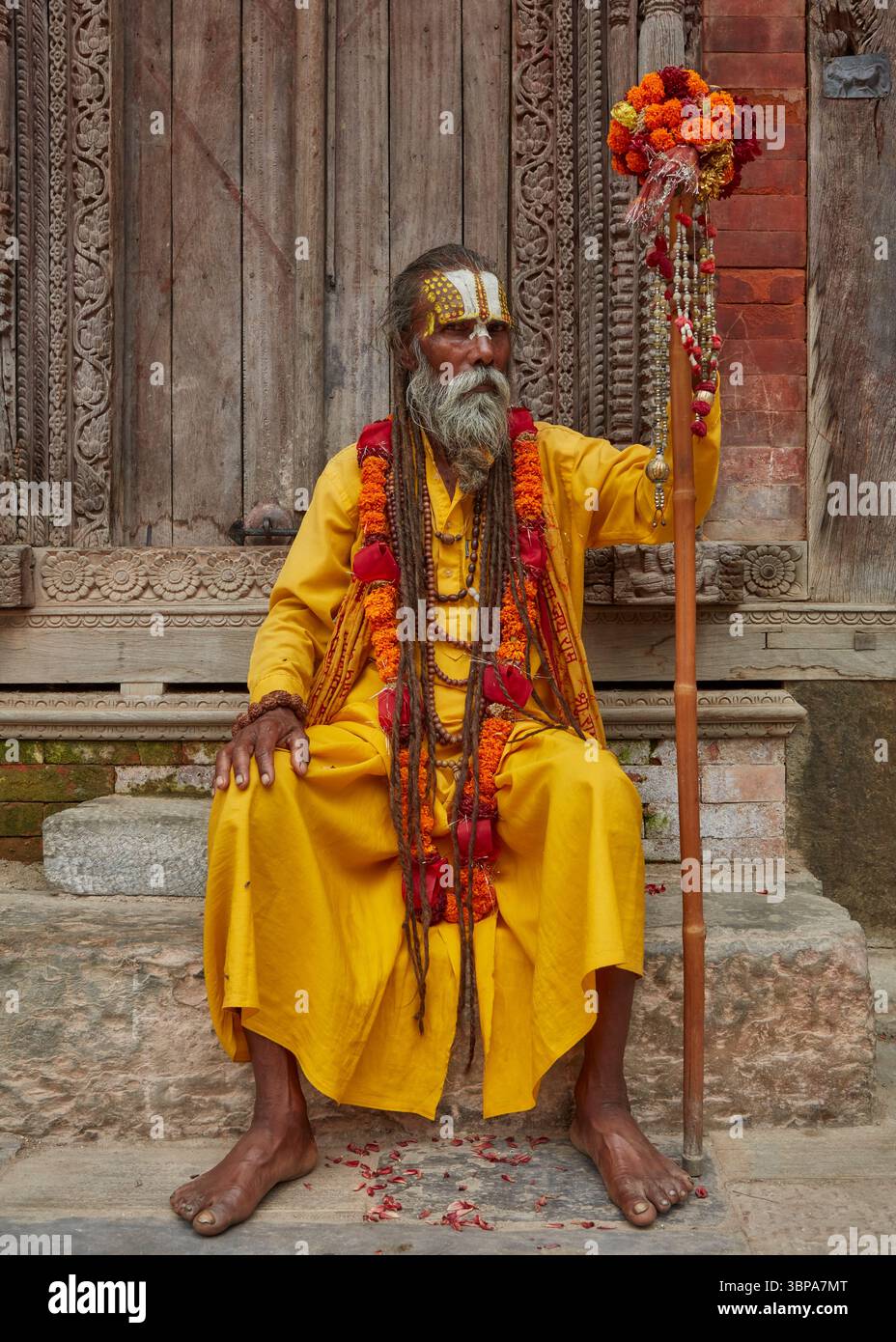 Portrait of a Sadhu holy man in traditional yellow robes, sitting near ...