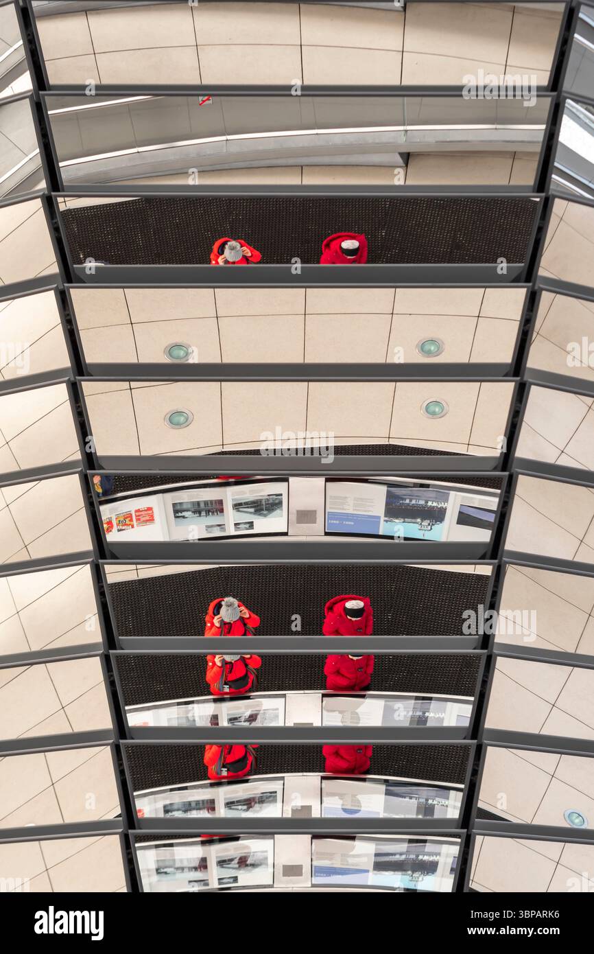 Visitors in red clothing reflected multiple times in the mirrored ...