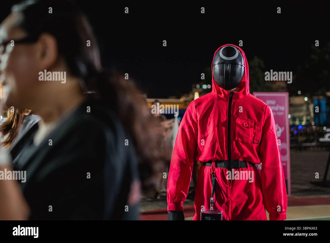 A performer dressed as a red-suited masked guard from Squid Game. On ...
