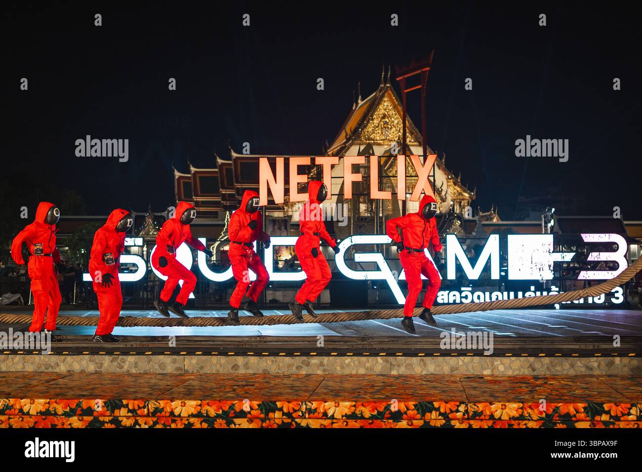 Performers dressed as red mask guards from Squid Game play jump a rope ...