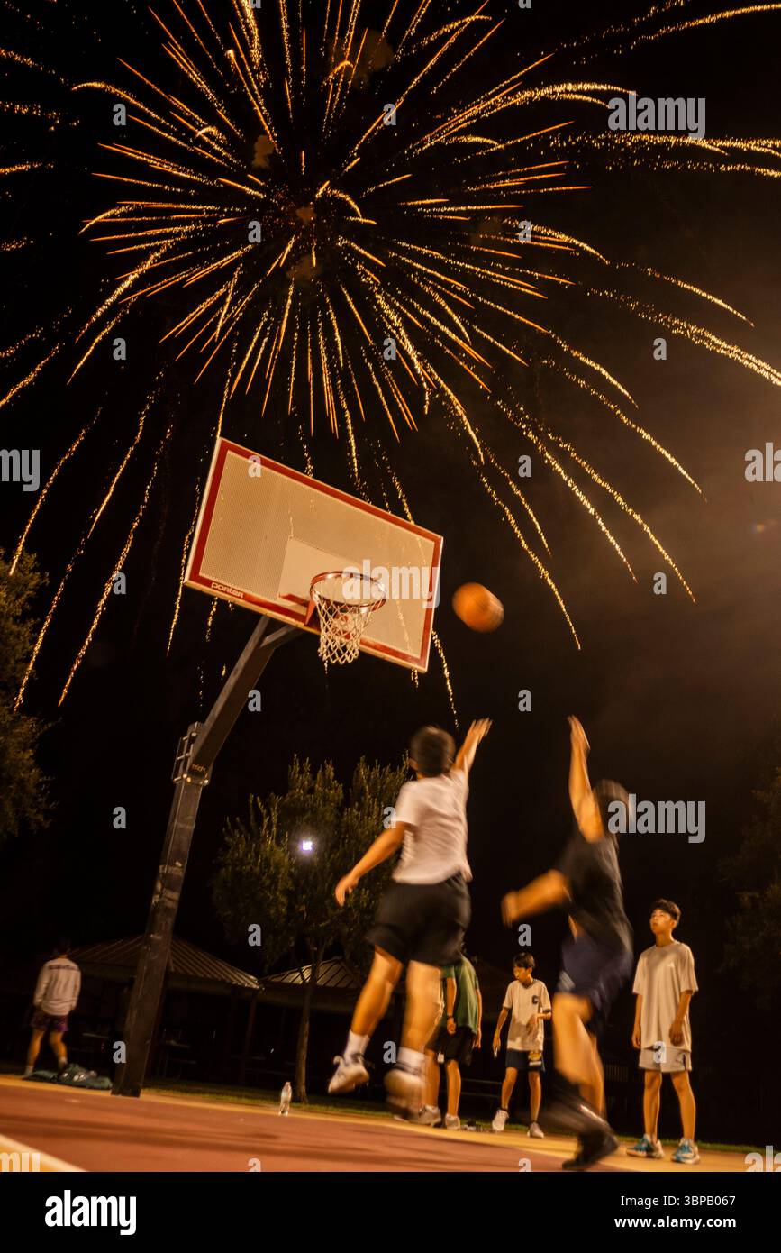 People play basketball amid fireworks under the night sky above the ...