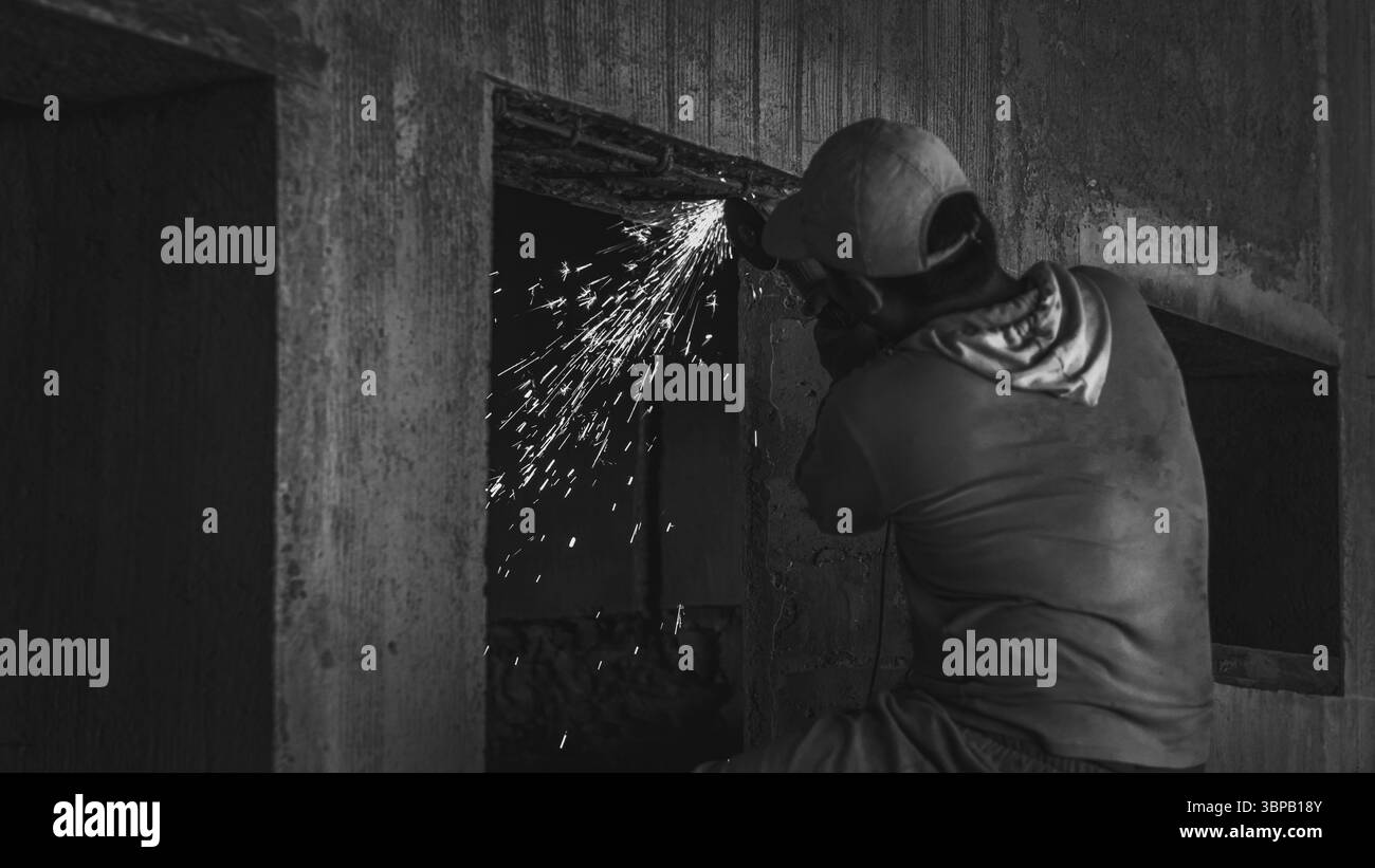 Construction worker cuts metal with a grinder, creating sparks in a ...