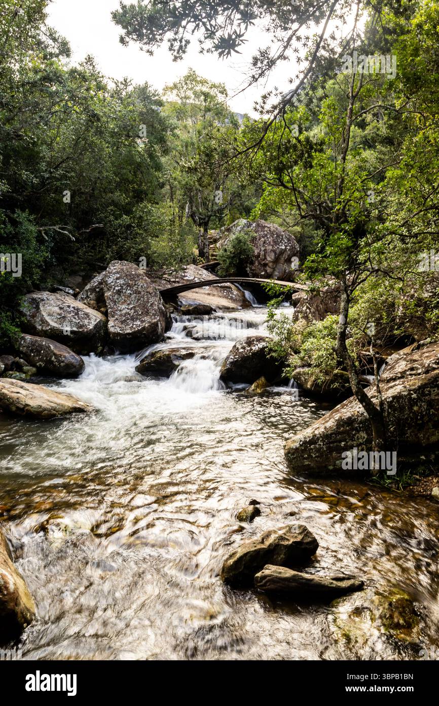 A small arched walking bridge crossing the Fast flowing Mahai river at ...
