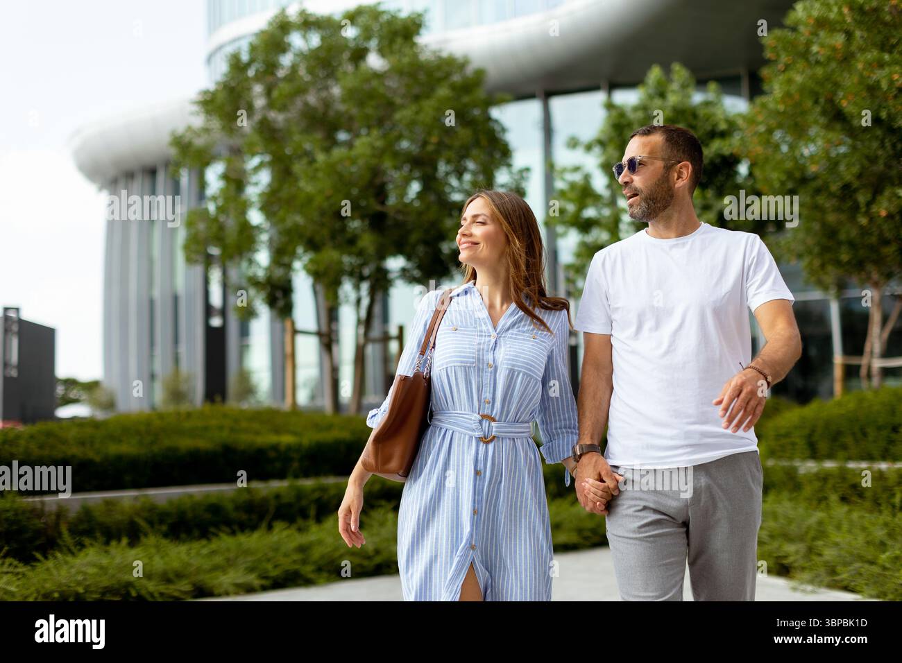 Two people walk together, radiating joy, in a modern urban park adorned ...
