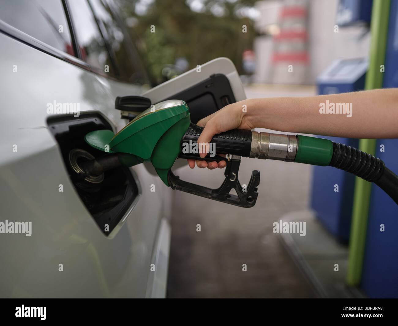 Close up of a person refueling a car at a gas station using a green ...