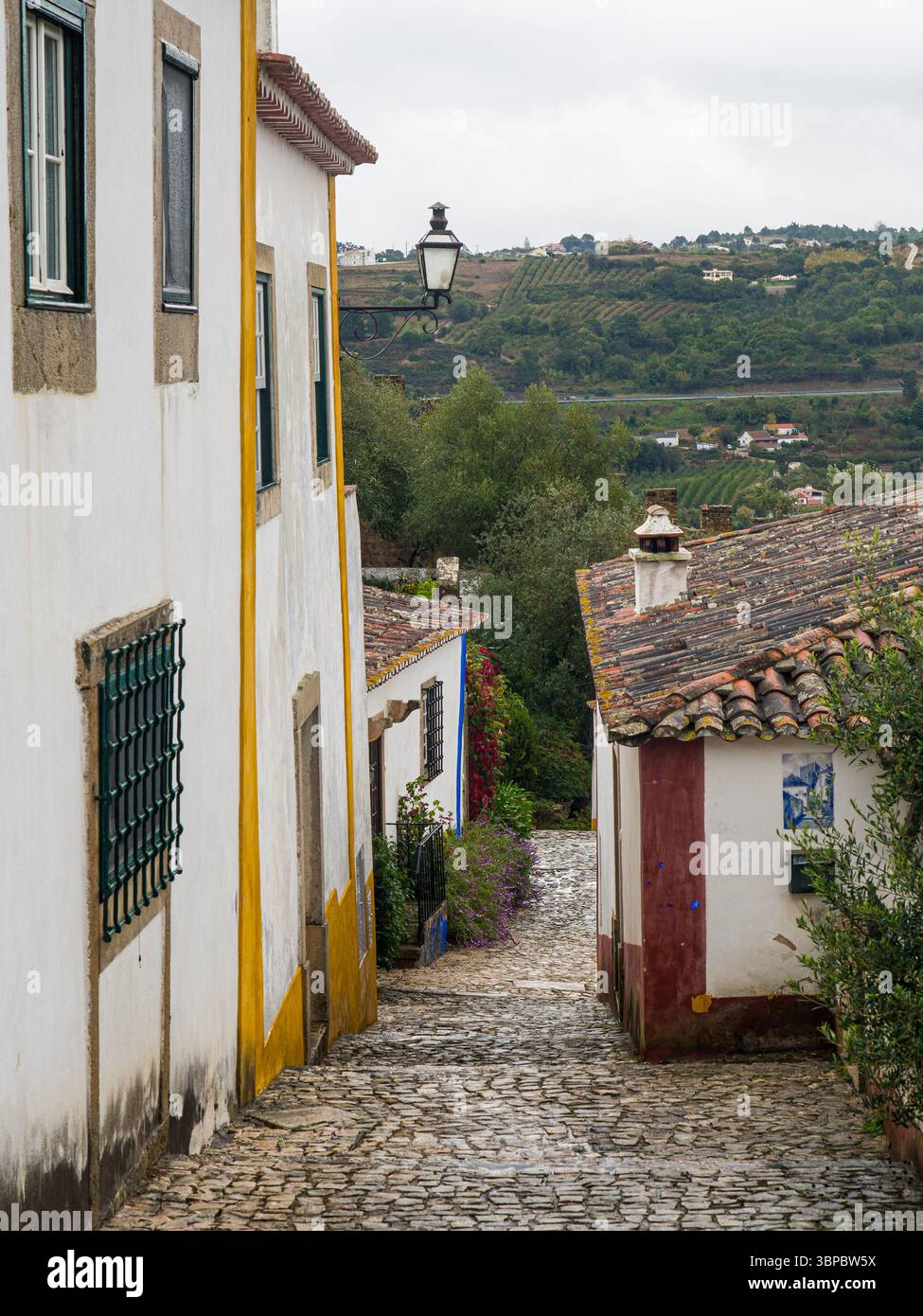 Winding wet cobbled street in Óbidos village after autumn rain ...
